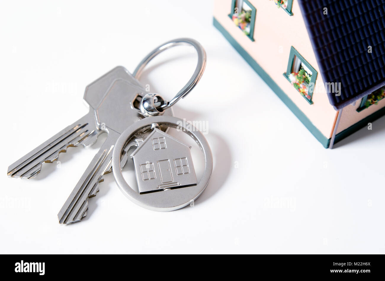 House key on a house shaped pendant. Real estate agent concept on white ...