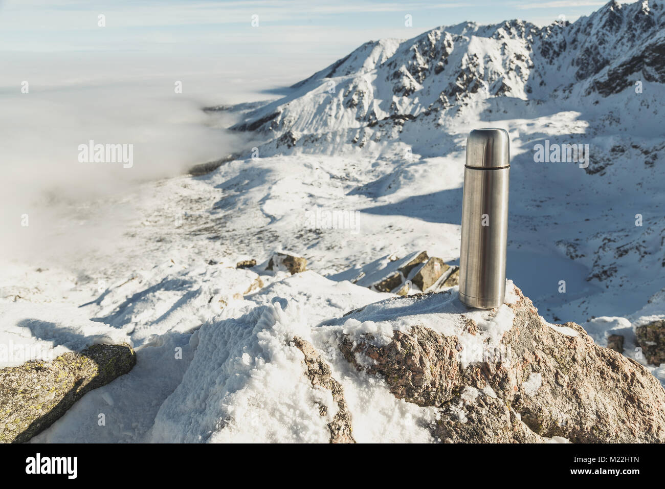 Classical steel thermos in winter in the mountains with mountains in ...