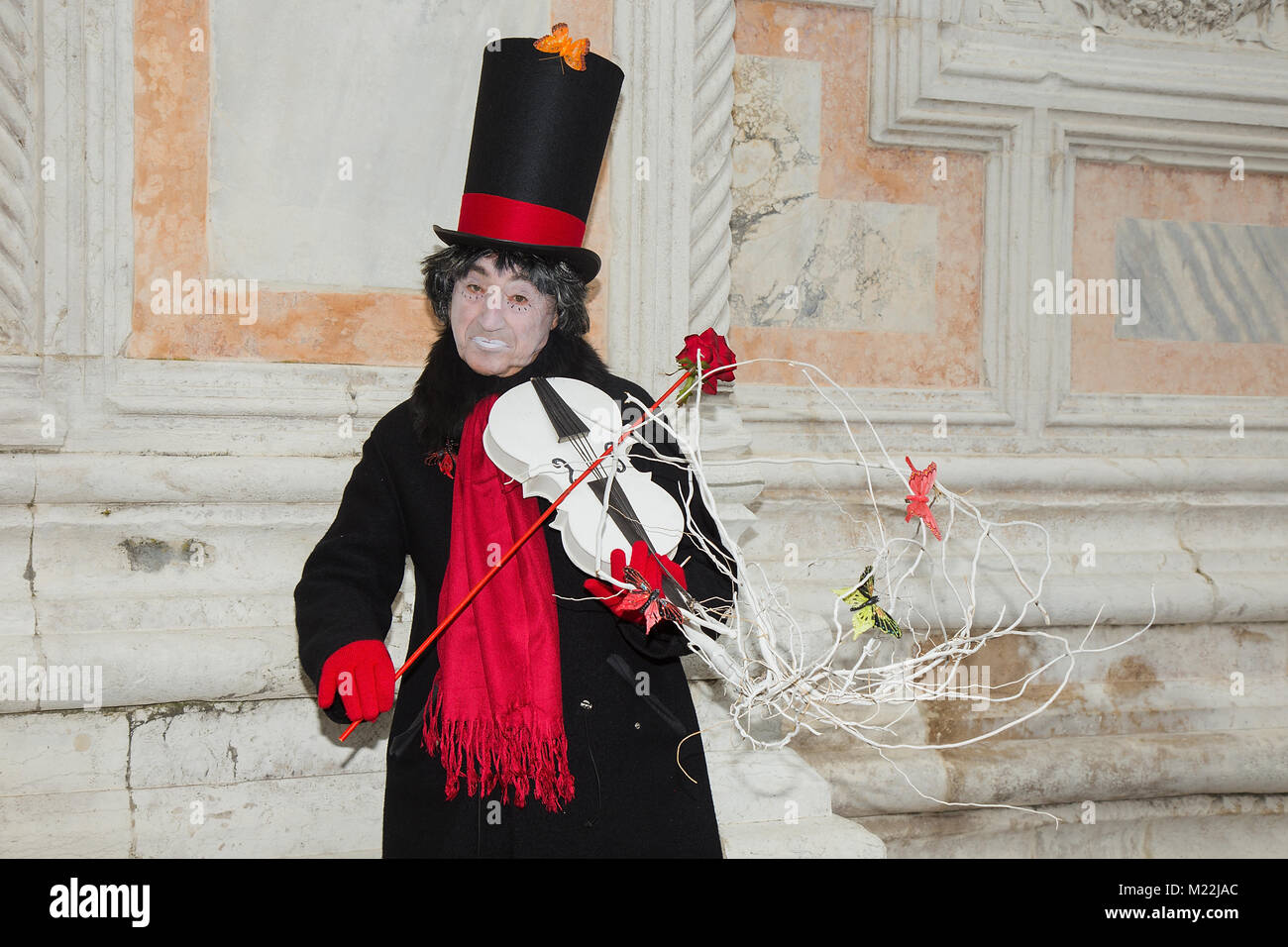 Male Pierrot playing violin with red rose on San Zaccaria Square ...