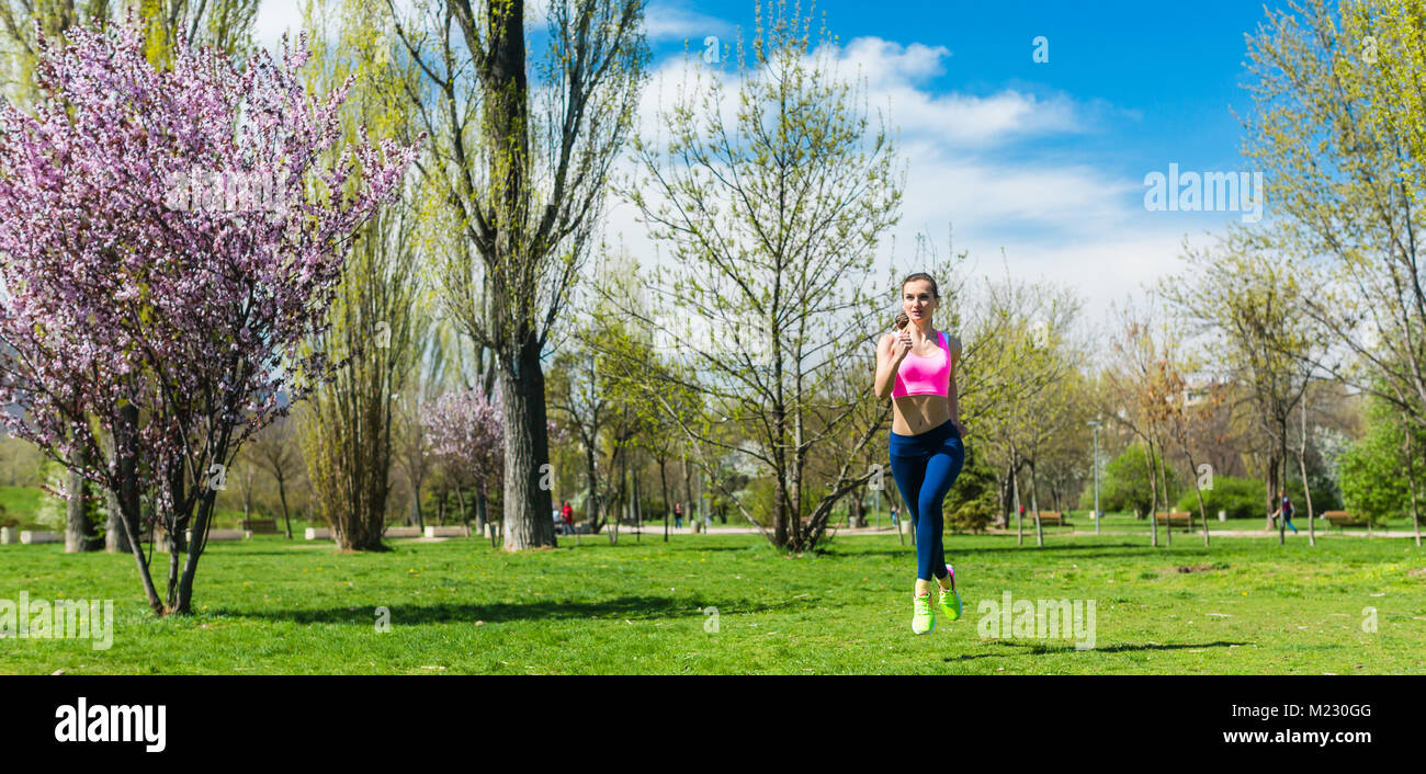 Woman running for better fitness though a park in spring Stock Photo ...