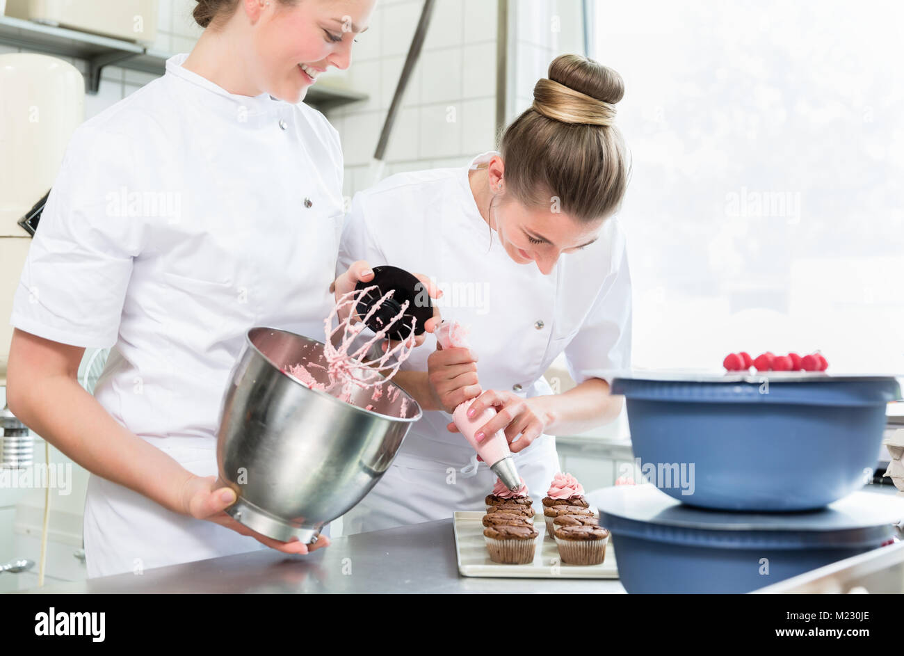 Pasty baker women putting cream on cakes Stock Photo - Alamy