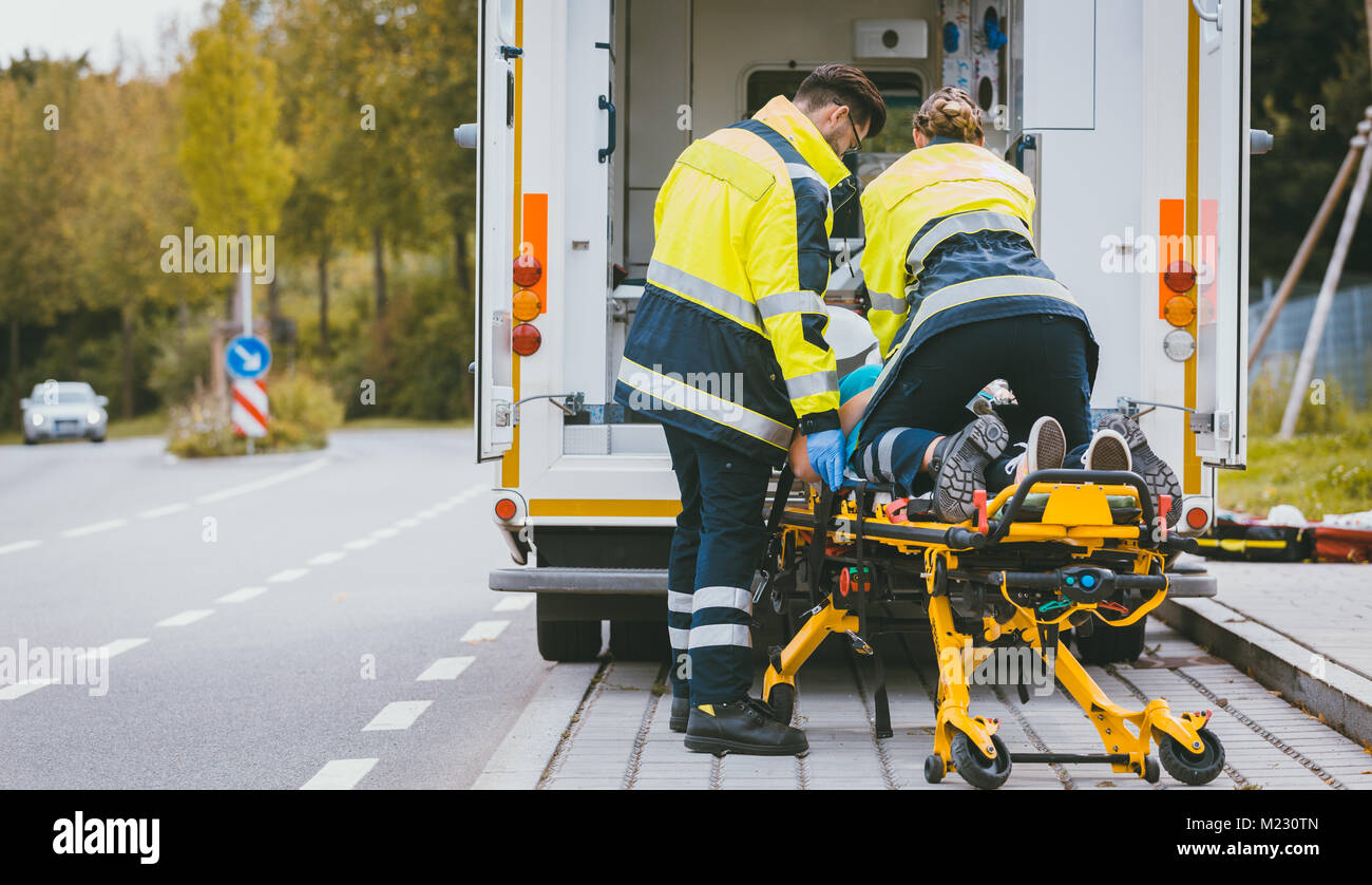 Paramedic on stretcher fighting for life of injured woman Stock Photo ...