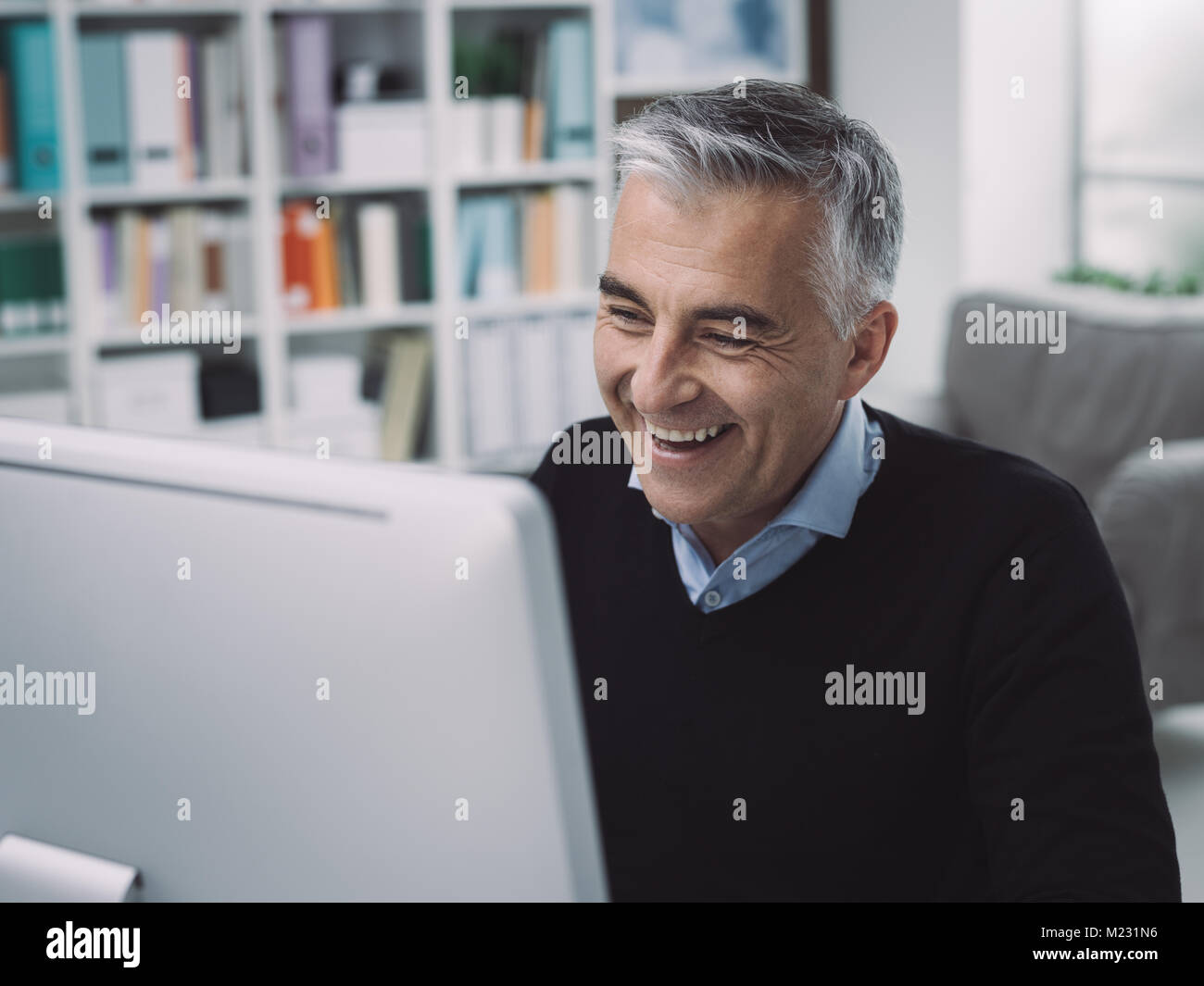 Happy confident manager working with his computer in the office, he is ...