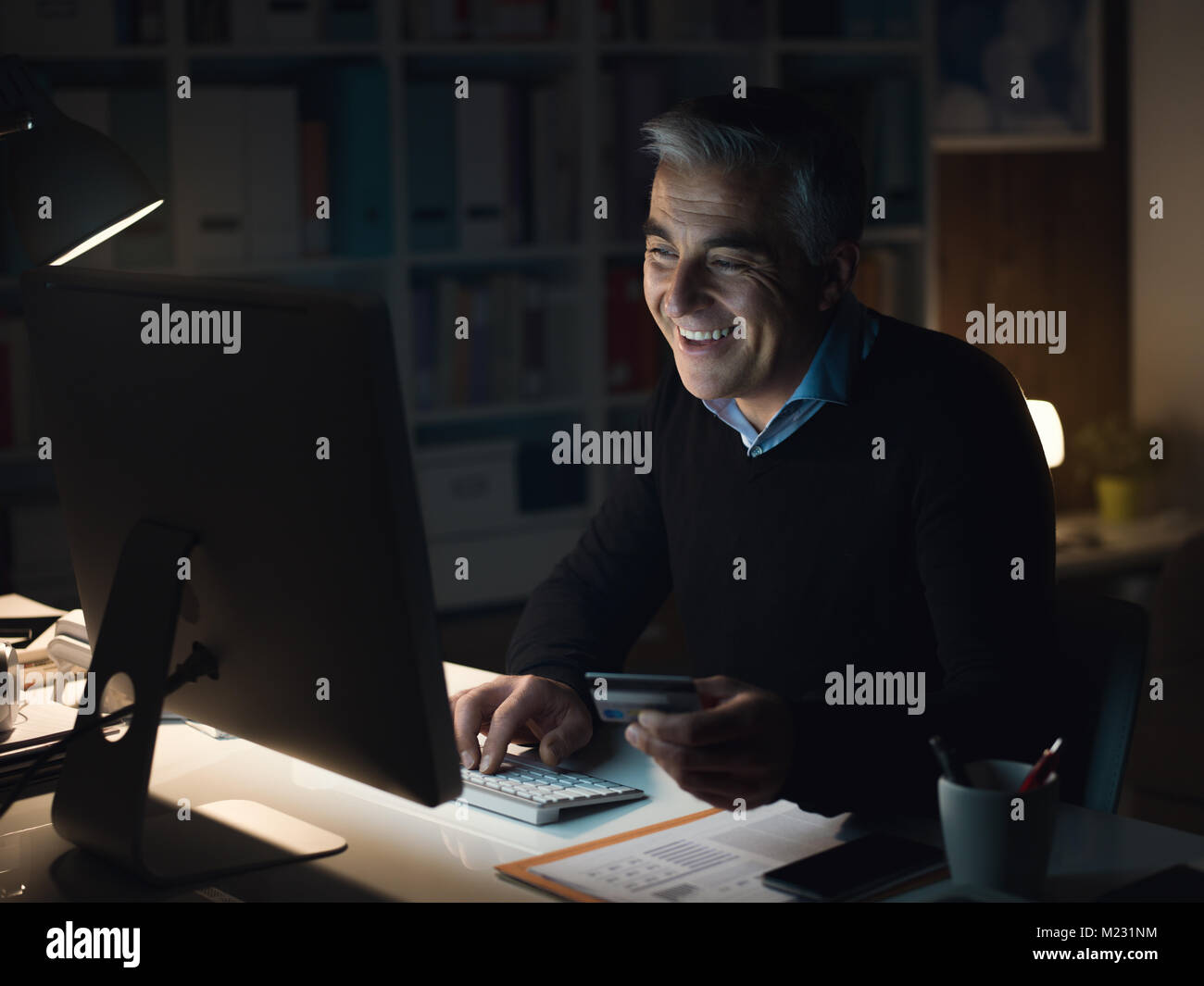 Smiling cheerful man connecting late at night with his computer and ...