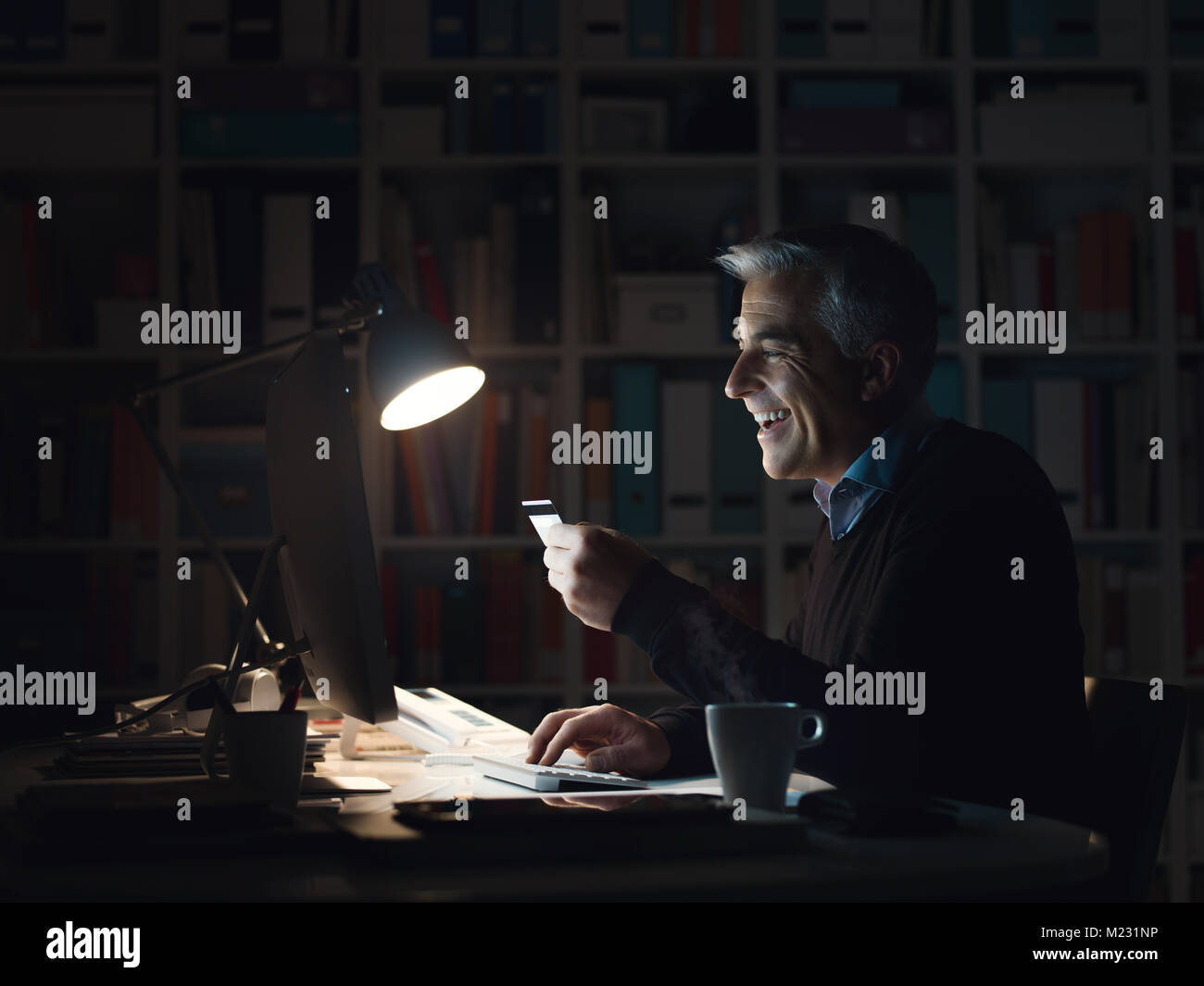 Smiling cheerful man connecting late at night with his computer and ...