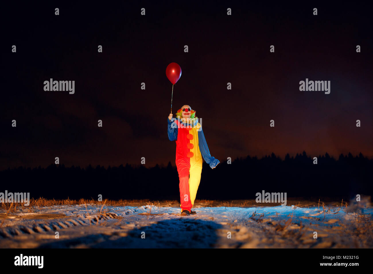 Full-length image of clown with colorful balloons at night Stock Photo ...