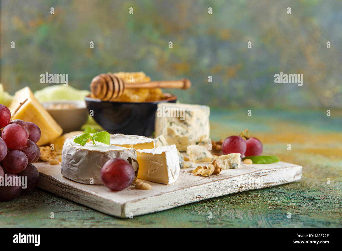 Different types of cheese, red grapes, honeycomb and nuts on a white ...