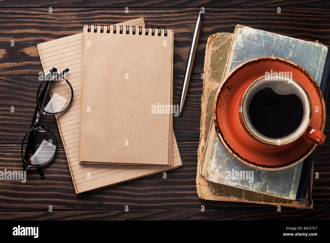 Retro table with vintage items. Coffee cup, books, notepad and glasses ...