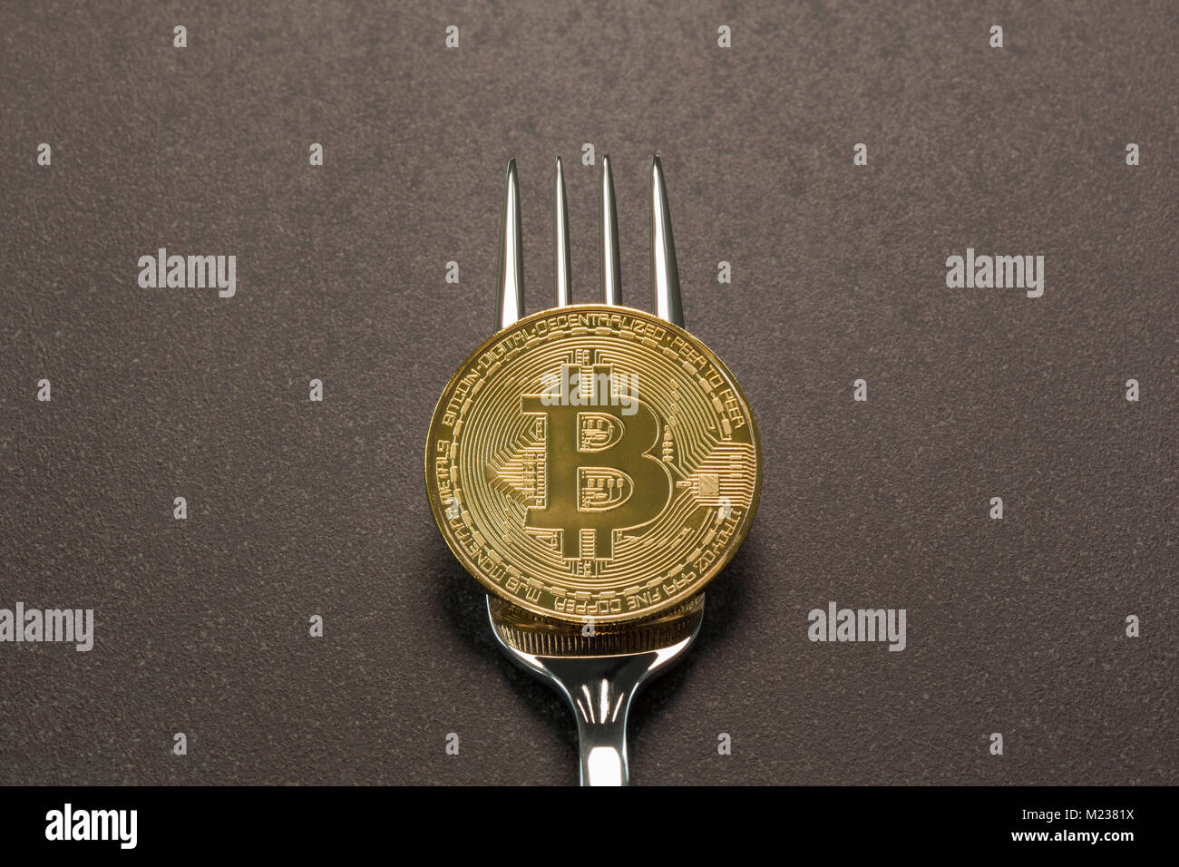 Golden Bitcoin physical coin on a fork illustrating a cryptocurrency ...