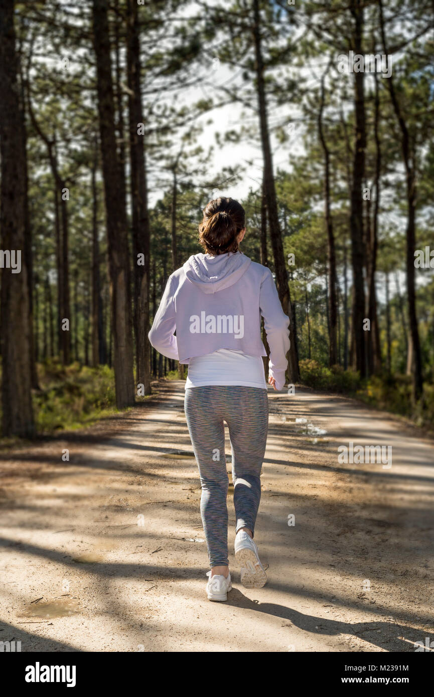 woman jogging through a forest, back view Stock Photo - Alamy