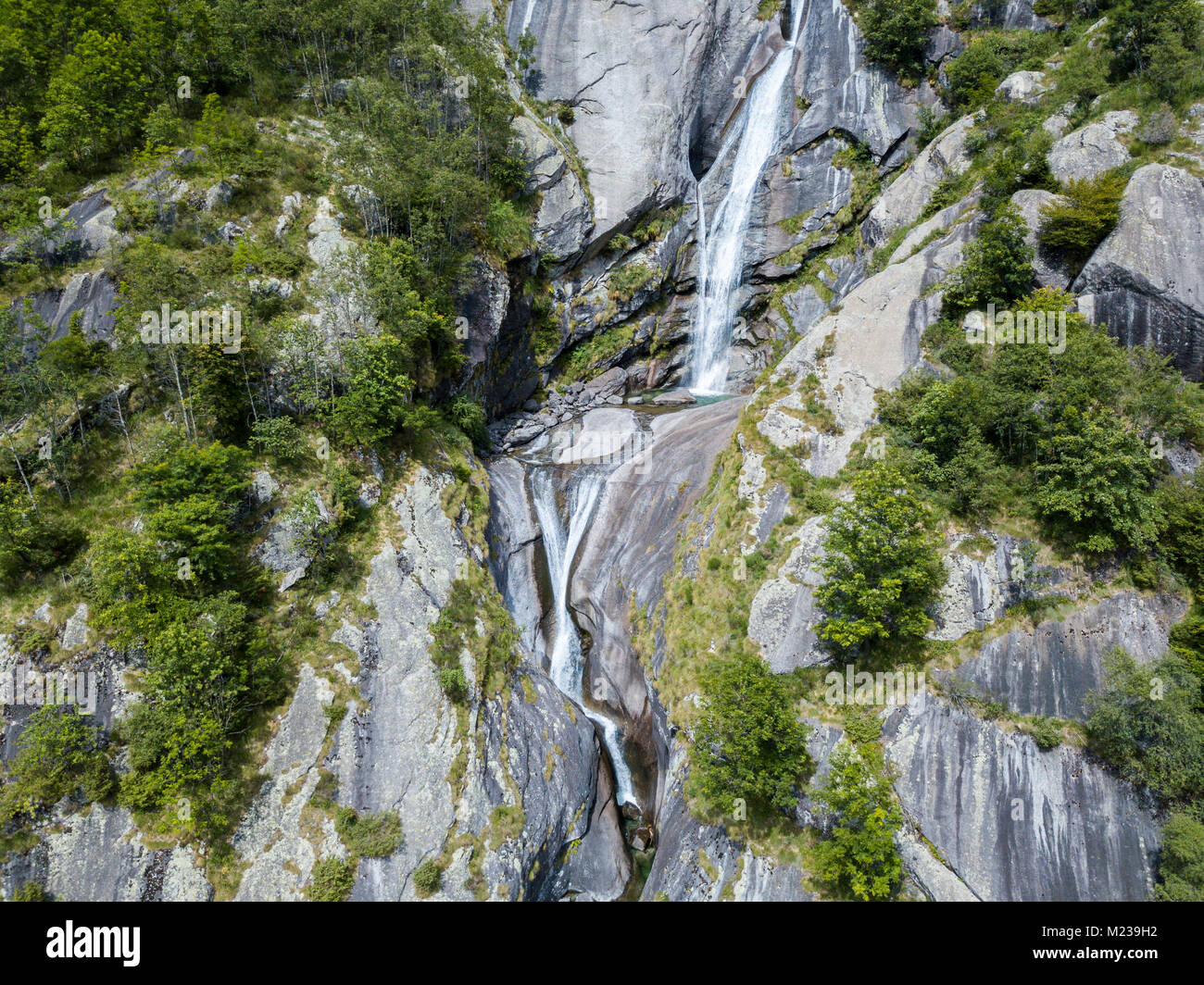 Aerial view of a waterfall in Val di Mello, a green valley surrounded ...