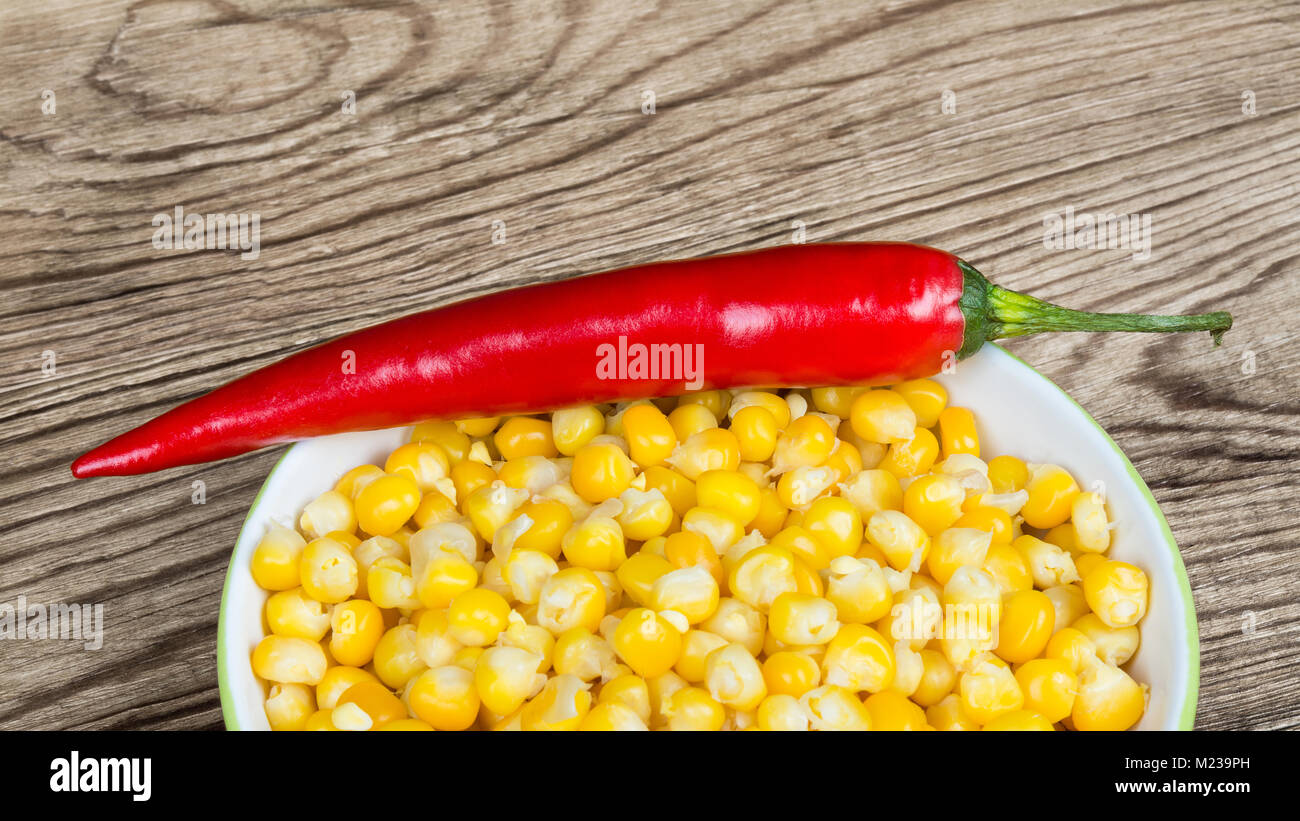 Detail of a bowl with boiled corn and hot pepper. Heap of yellow maize ...