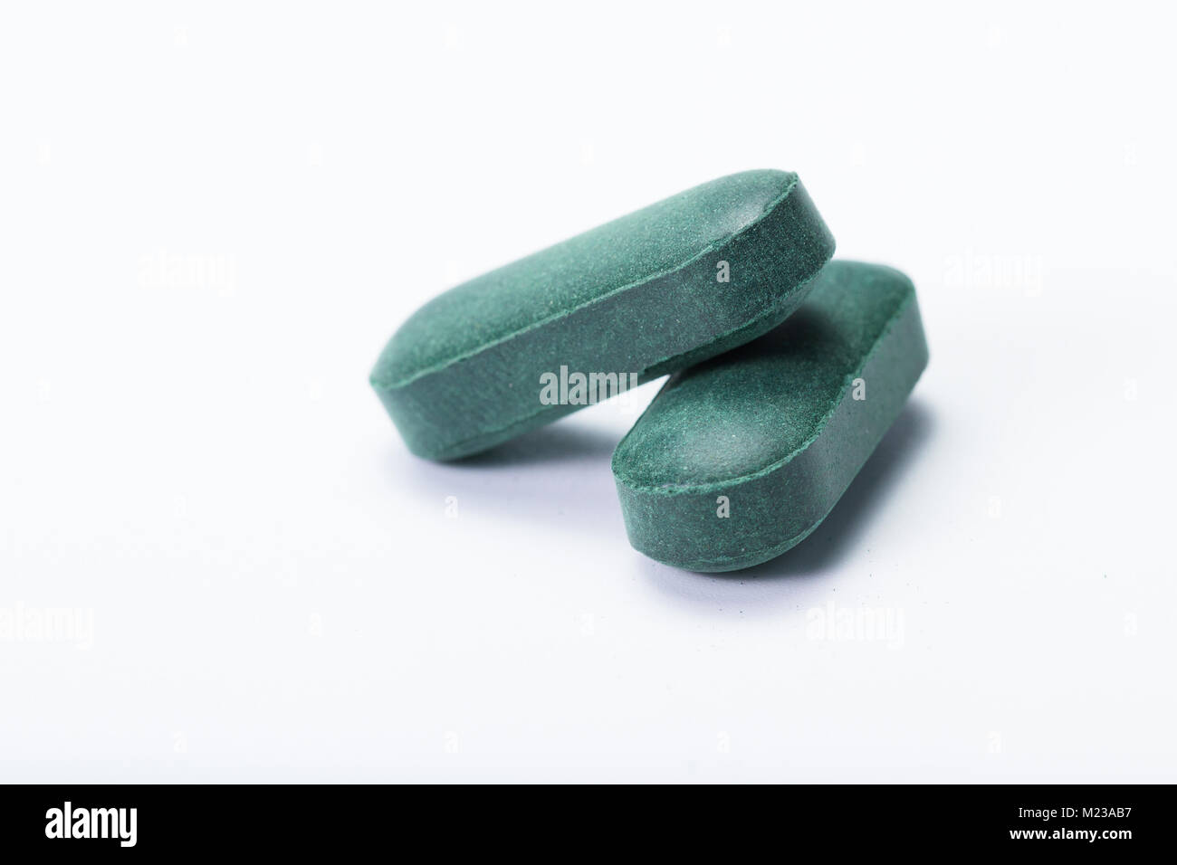 close cup of a serving dose of fermented spirulina tablets isolated on ...
