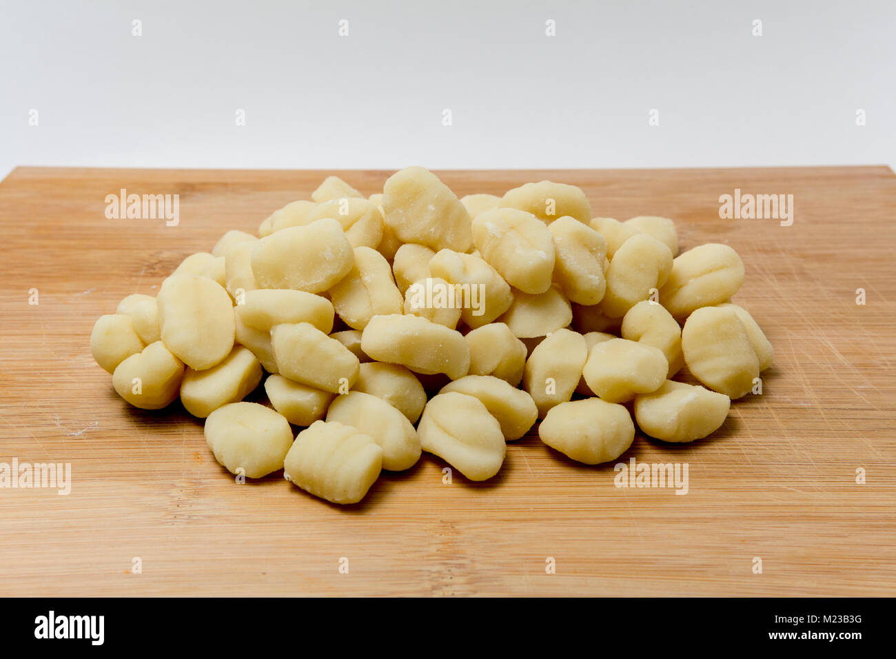 Closeup on raw potato gnocchi on wooden board, against white wall Stock ...