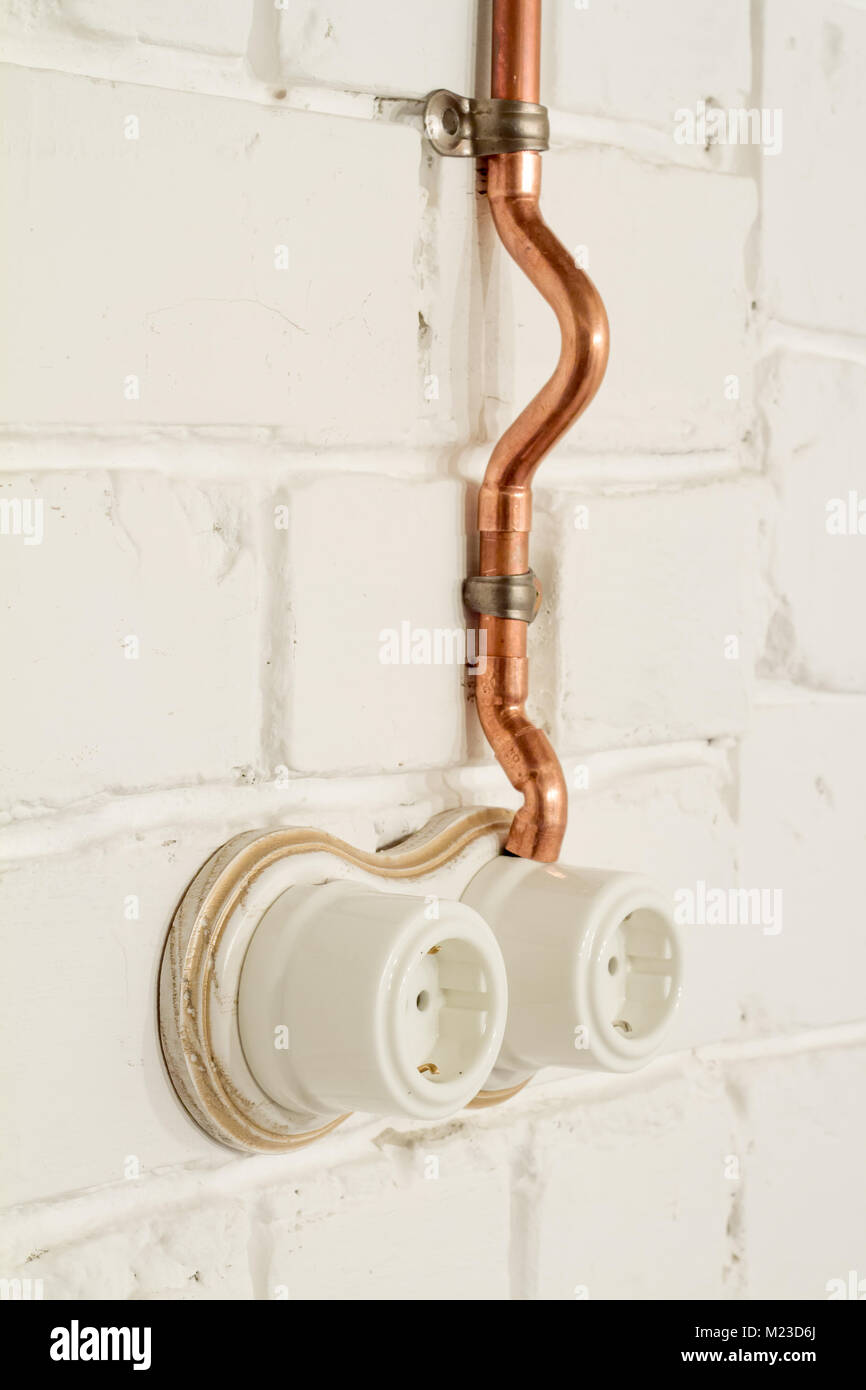 Retro socket made of white ceramic with open electrical wiring. Against ...