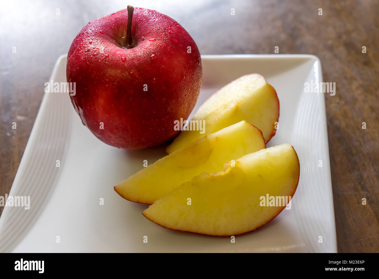 Red apple on a white square plate, Sliced fresh red apple on a white ...