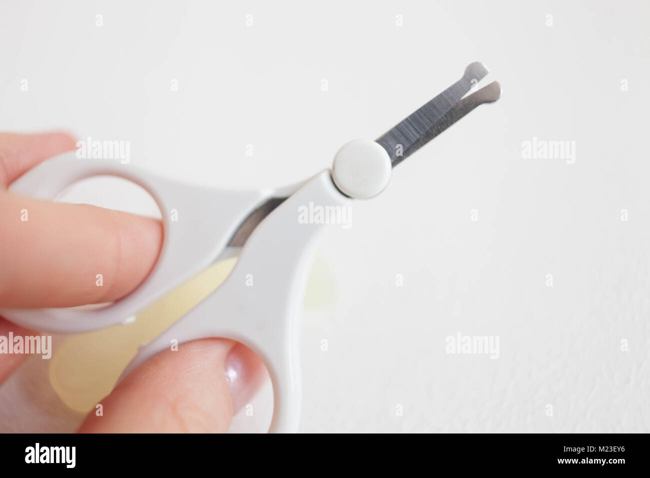 Baby scissors with rounded ends in the hands of his mother on a white ...