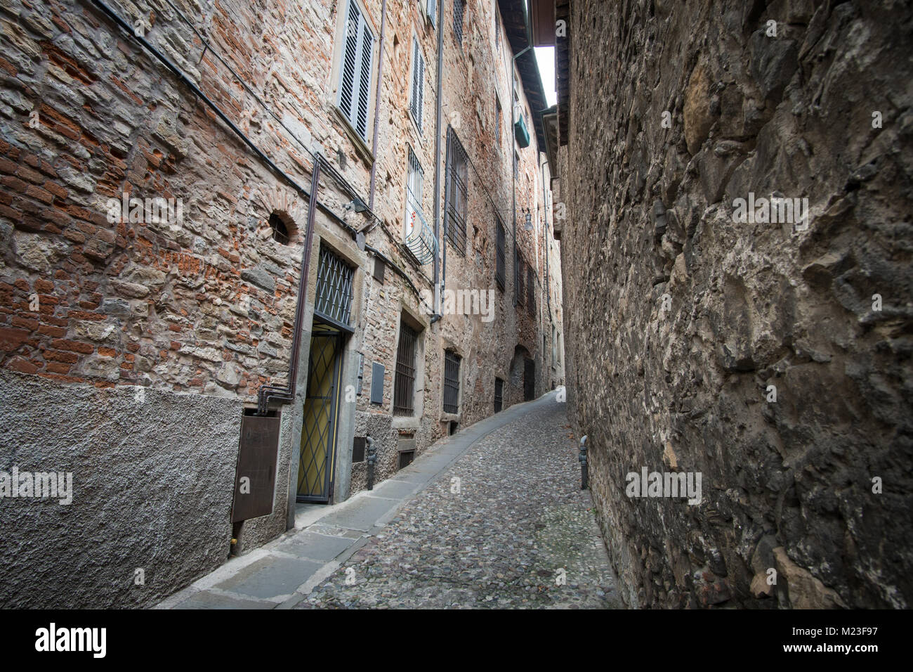 Dark narrow cobblestone street passage between old houses in a small ...