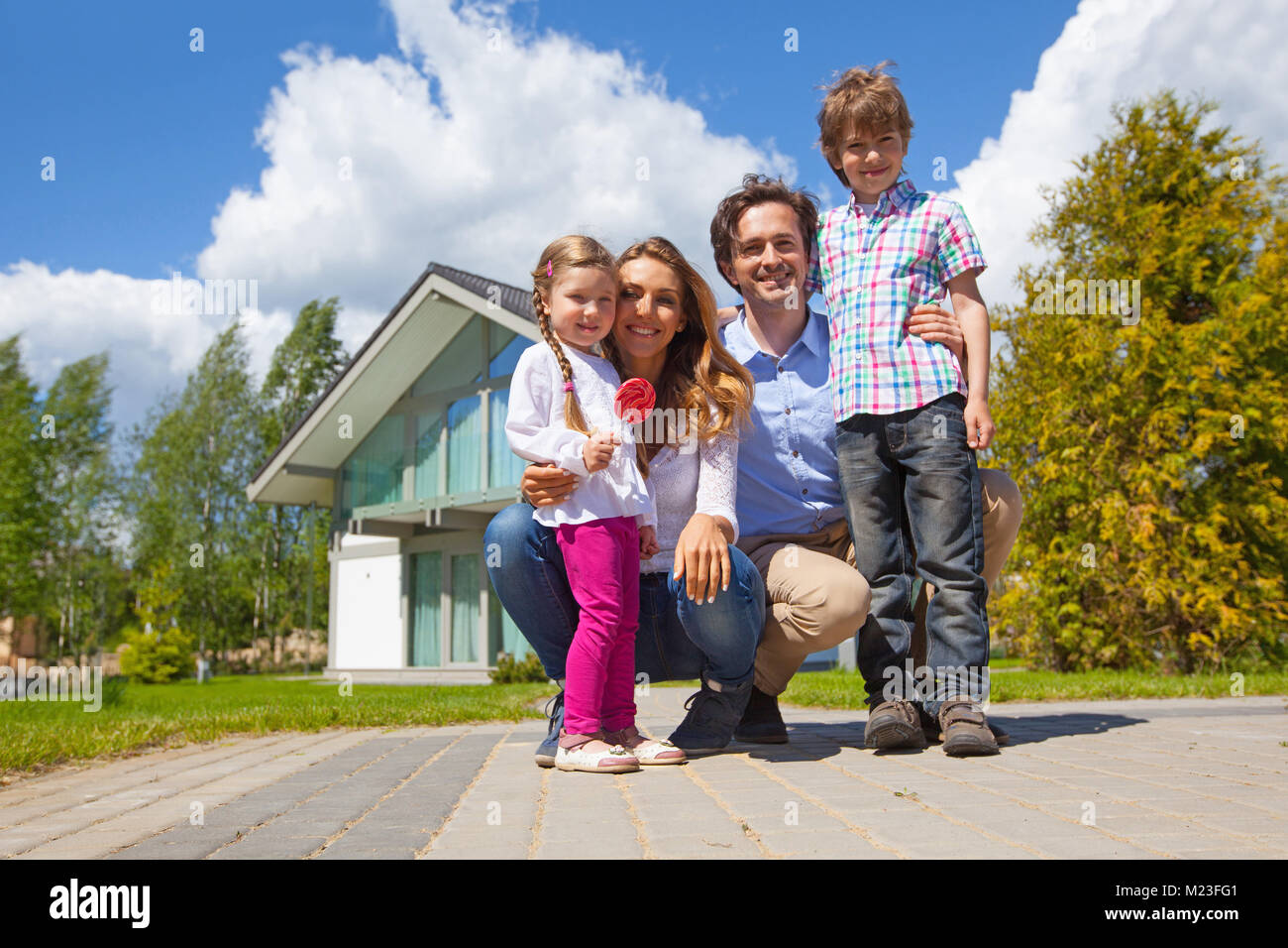 Portrait of happy smiling family and their children near their house ...