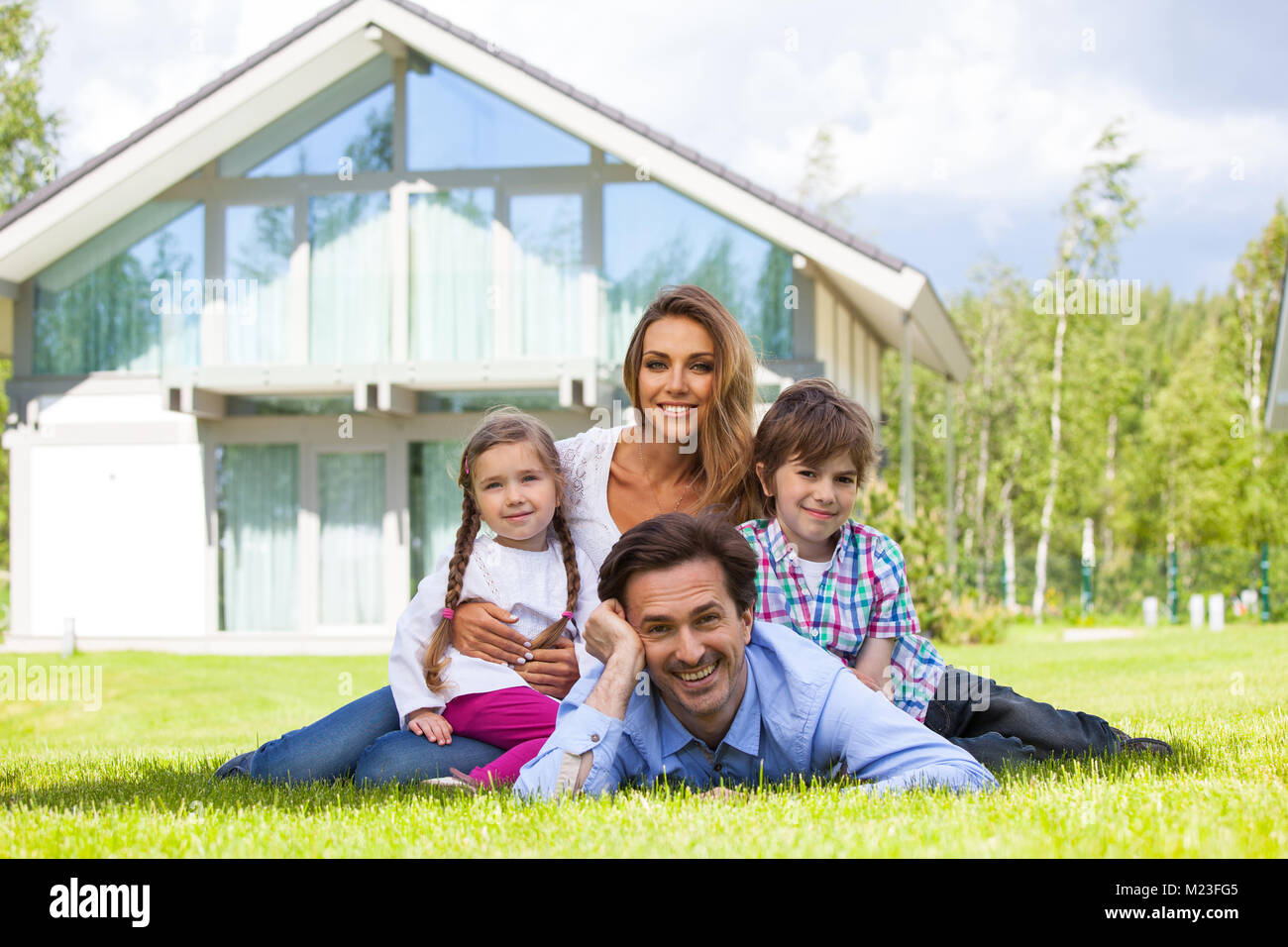 Portrait of happy smiling family and their children near their house ...