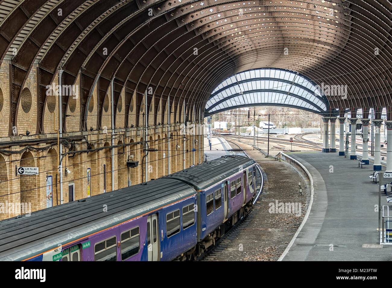 A train, ready for departure, rests on a gentle curve under an elegant ...