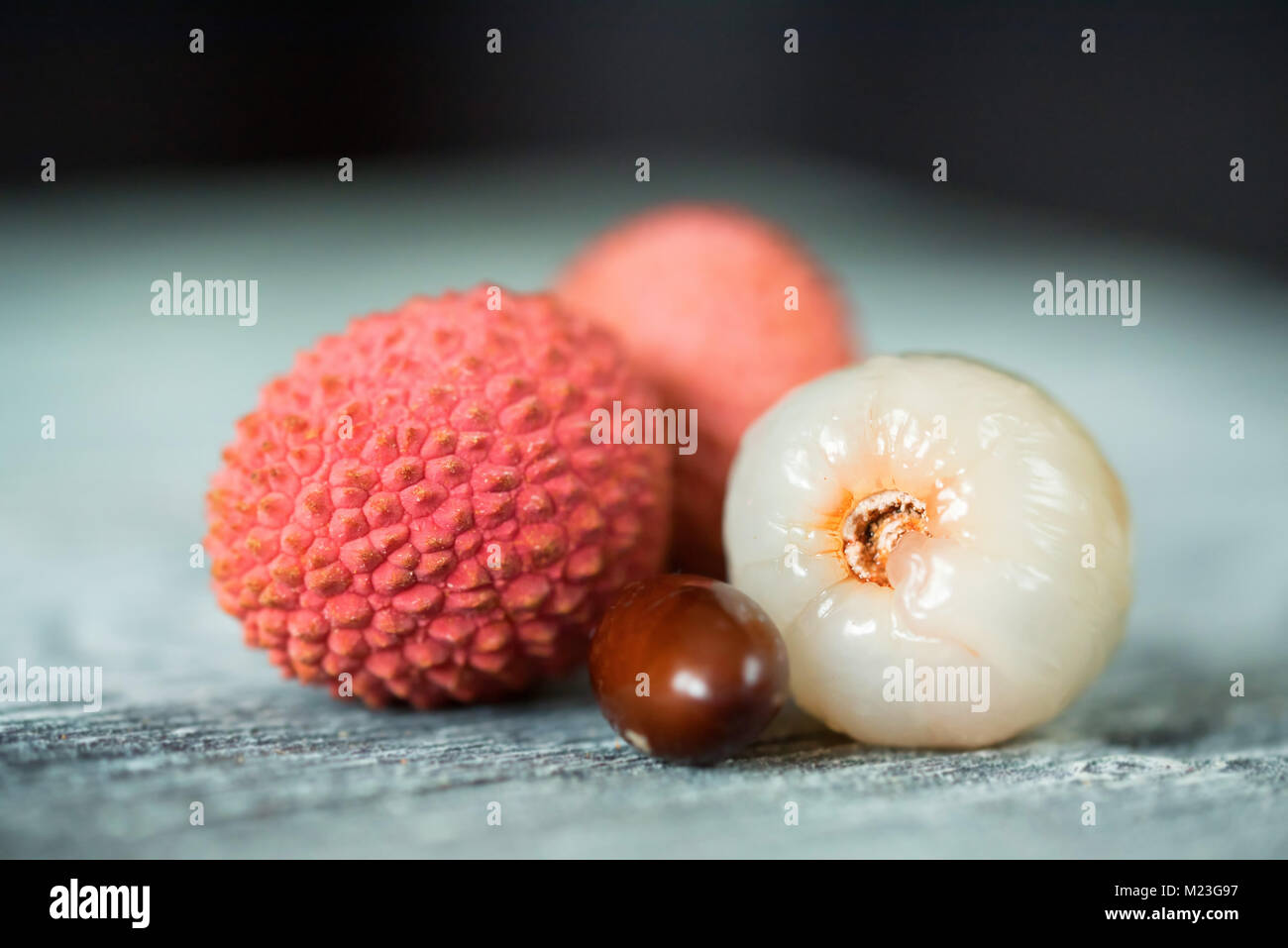 Three lychee fruits and seed on wooden background Stock Photo - Alamy