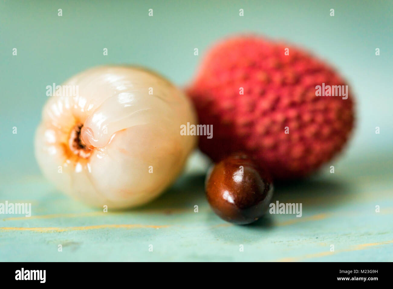 Two lychee fruits and seed wooden background Stock Photo - Alamy