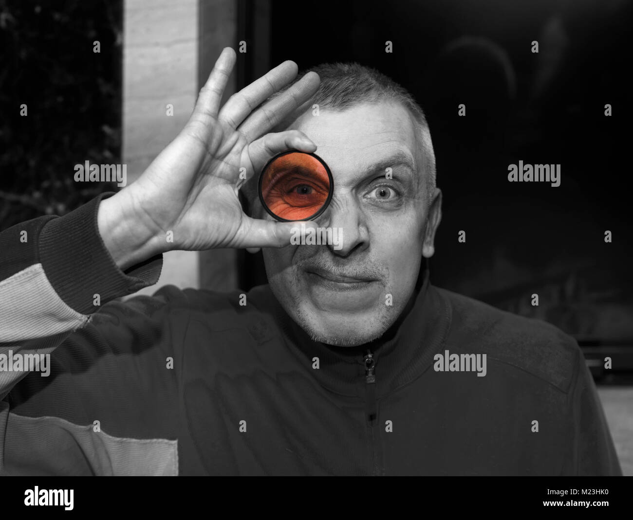 A strange looking man making face looking through a magnifying glass ...