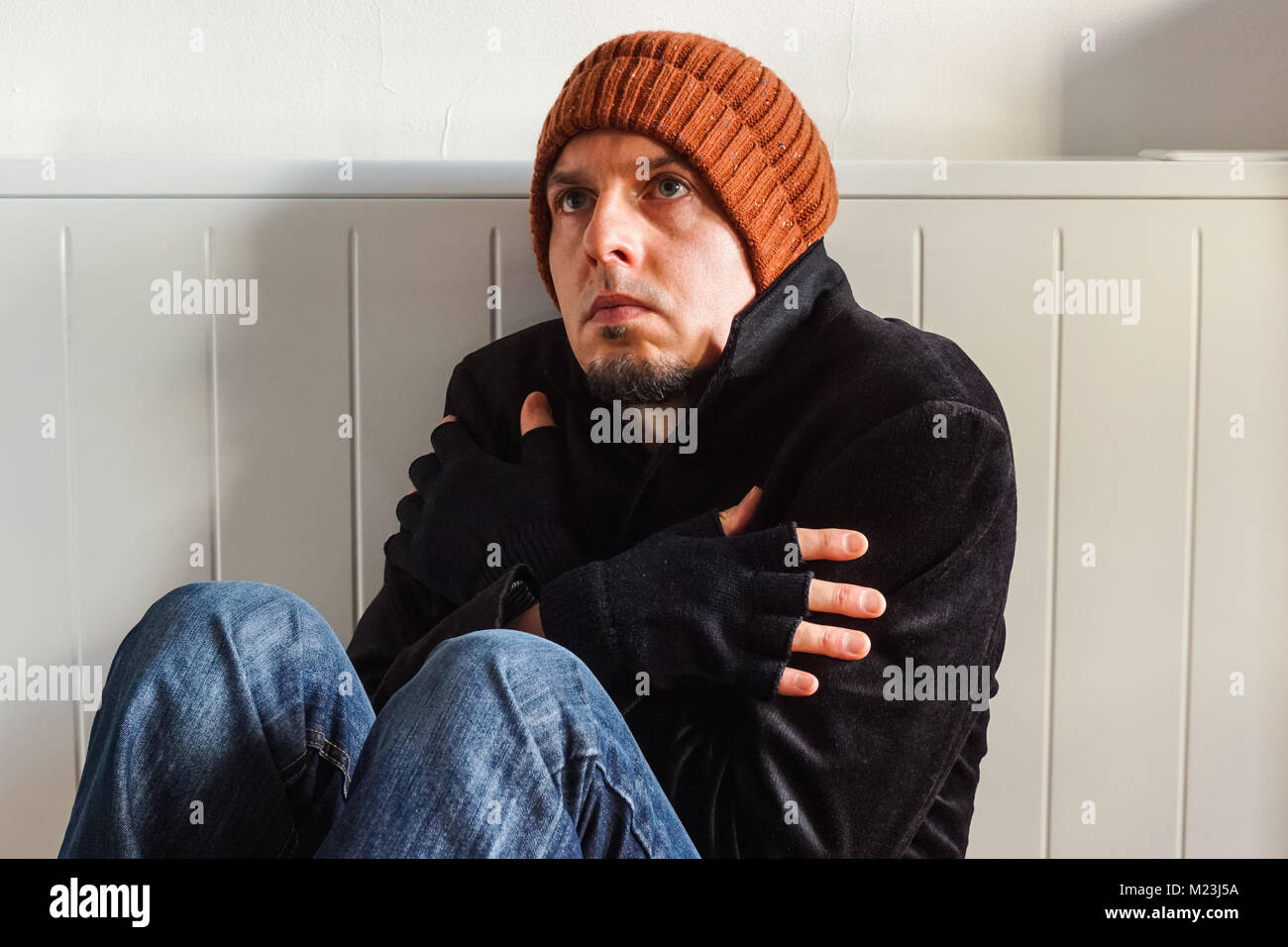 Cold young man next to radiator Stock Photo - Alamy