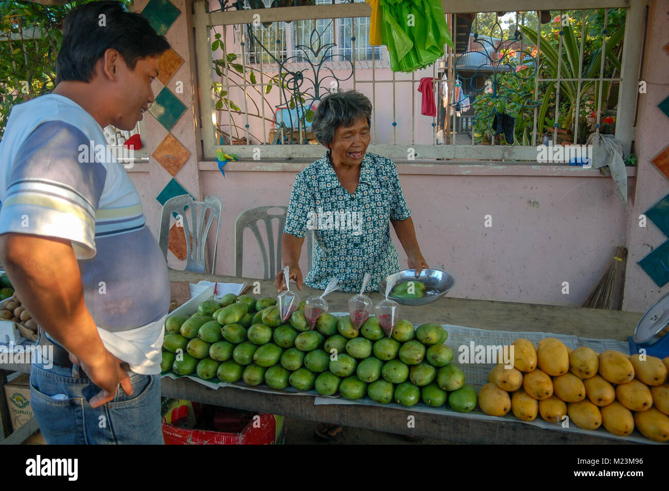 A Filipino man buys mangoes from an old lady running a sell selling ...