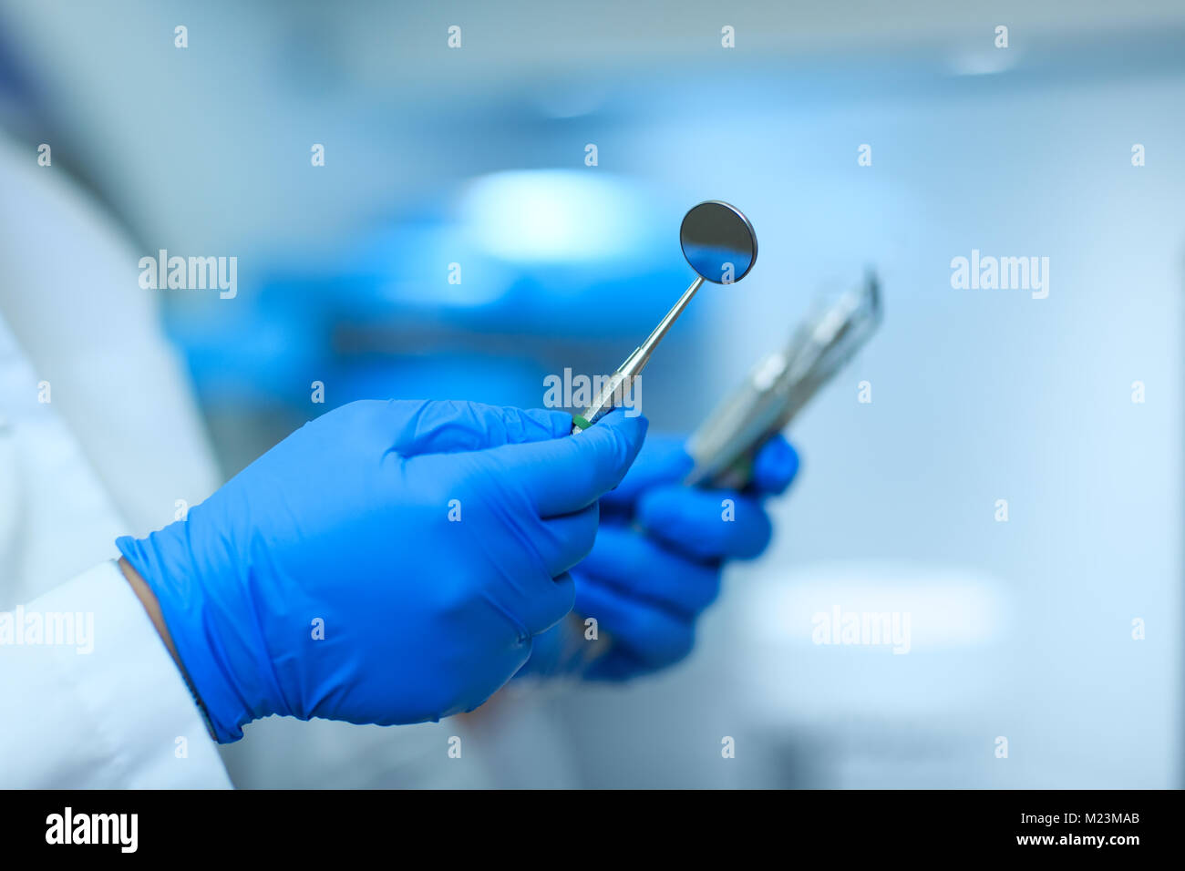 Dentist holding mirror and periodontal explorer during surgery. Dentist ...