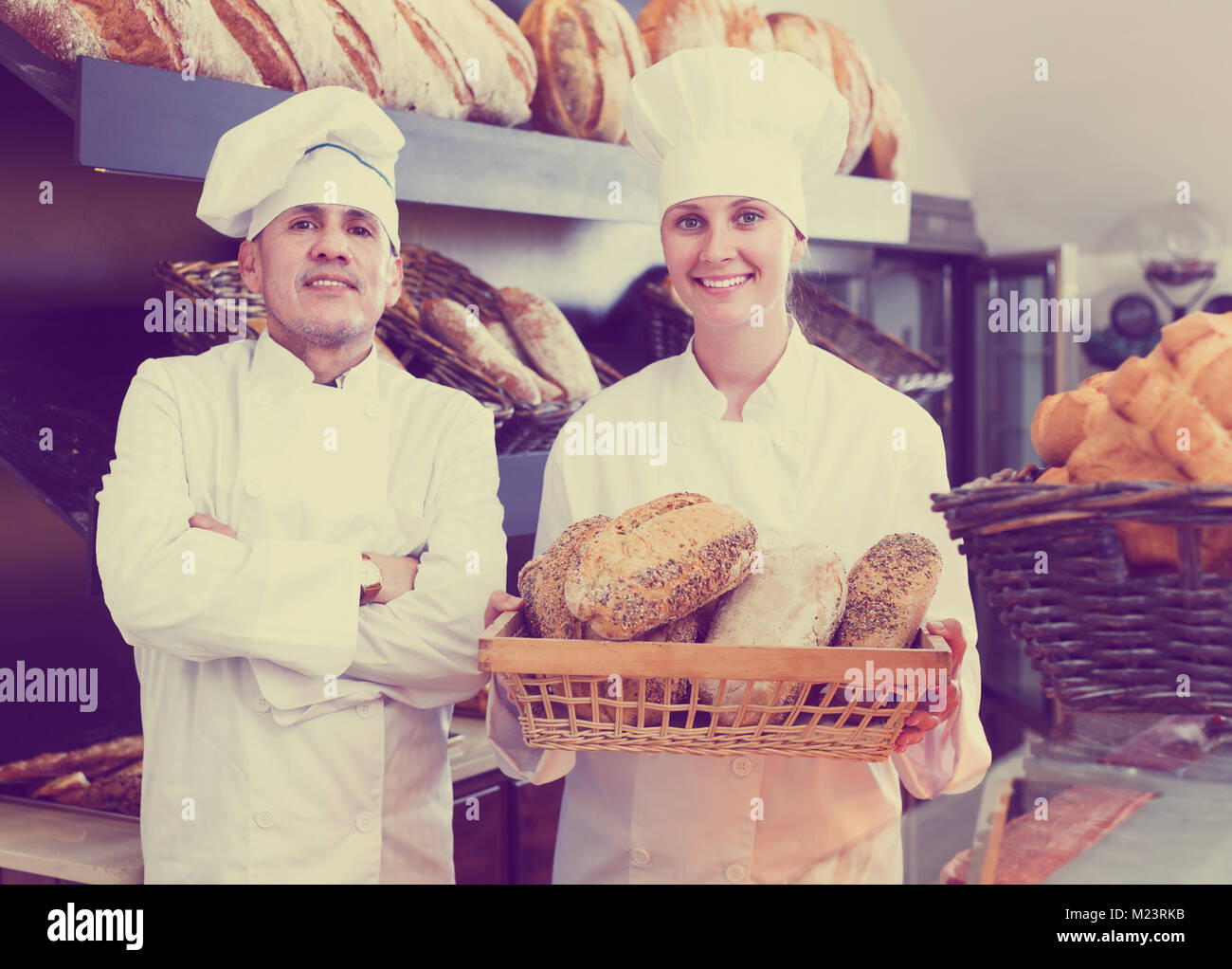 Portrait of man and women bakery employees offering delicious bread in ...