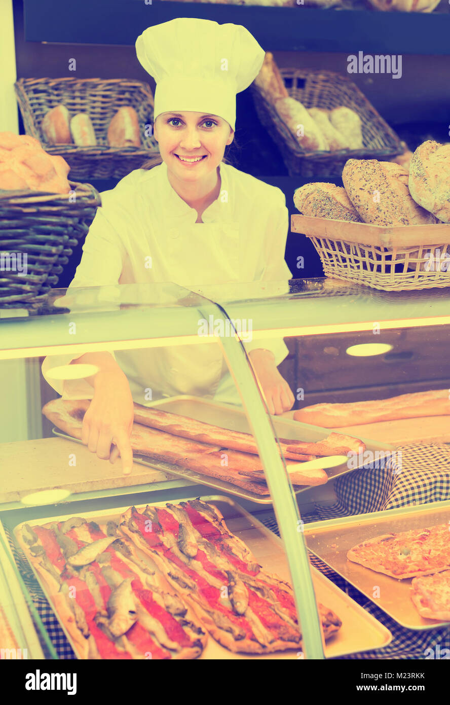 Portrait of young happy female bakers with tasty bread with fish ...