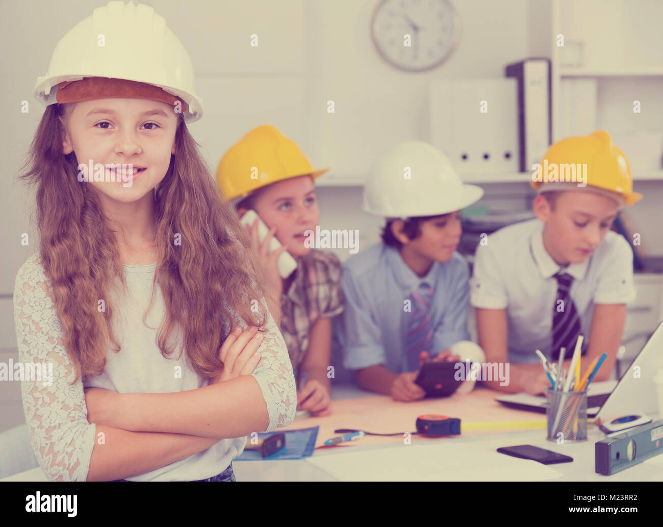 Girl in color helmet builder with collective architects near notebook ...