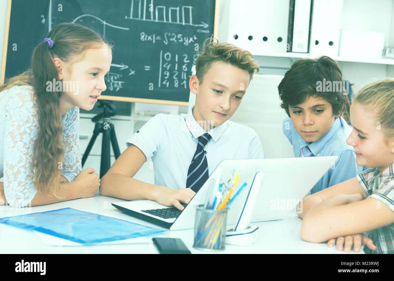 Boys and girls pupils talking near the notebook in the math class Stock ...