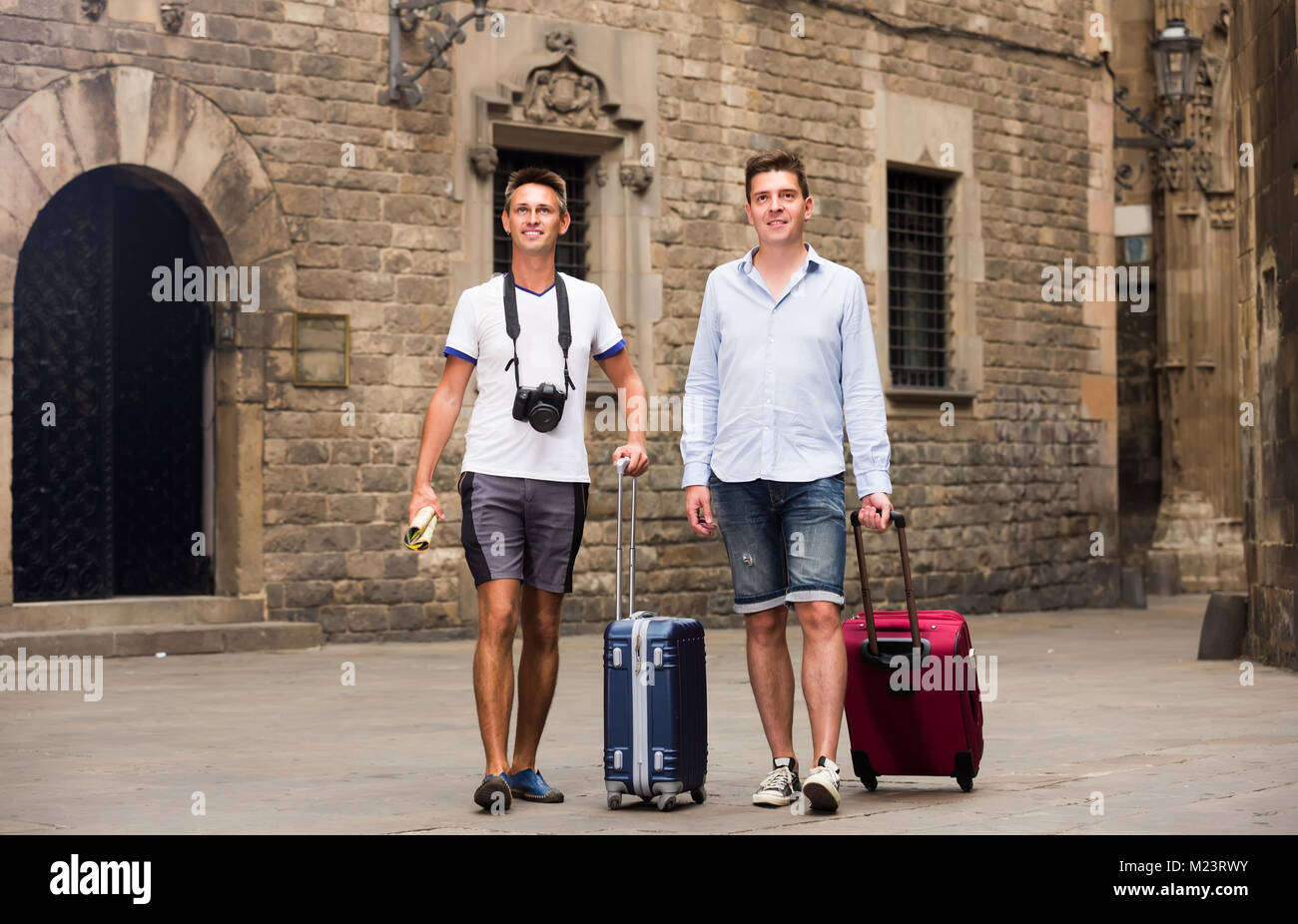 positive italian male couples with travel bags walking the city Stock ...