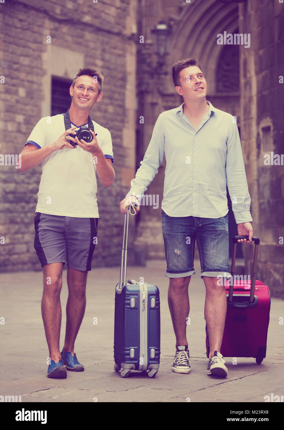 Cheerful male couple sightseeing and taking pictures of Europenian city ...