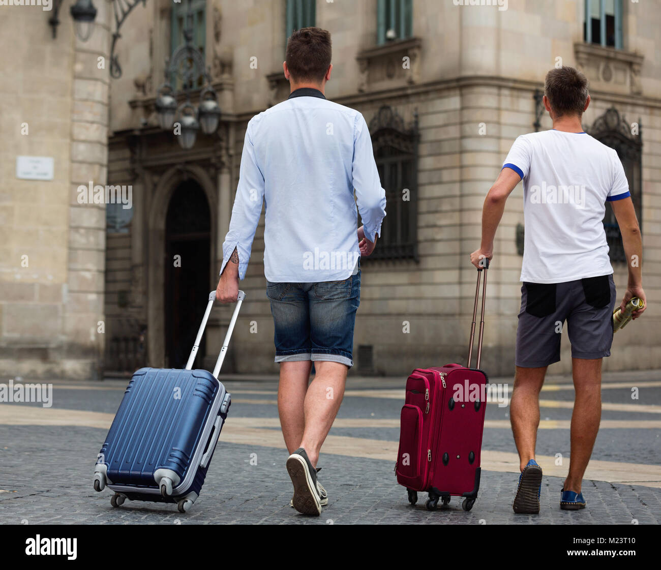 Rear view of happy cheerful positive men with baggage in street Stock ...