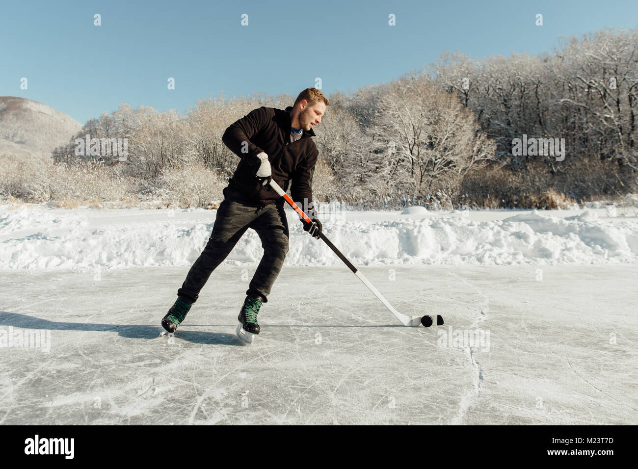 Man playing ice hockey on a frozen lake Stock Photo - Alamy
