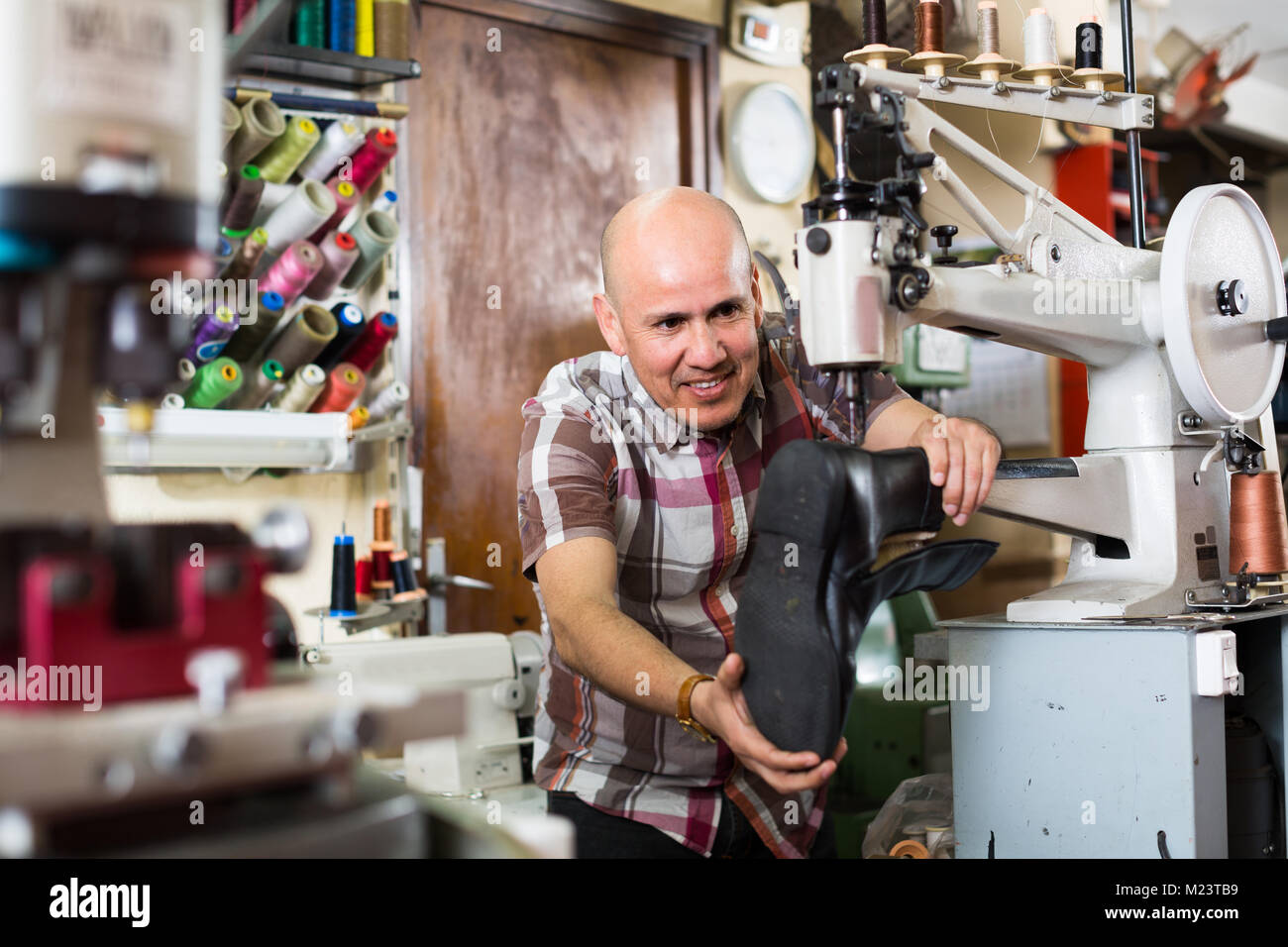 old specialist stitching shoes on leather sewing machine at factory ...