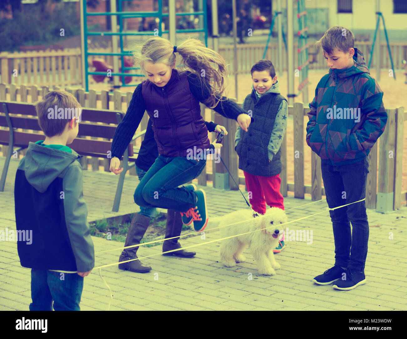 Positive children skipping on chinese jumping elastic rope in yard ...