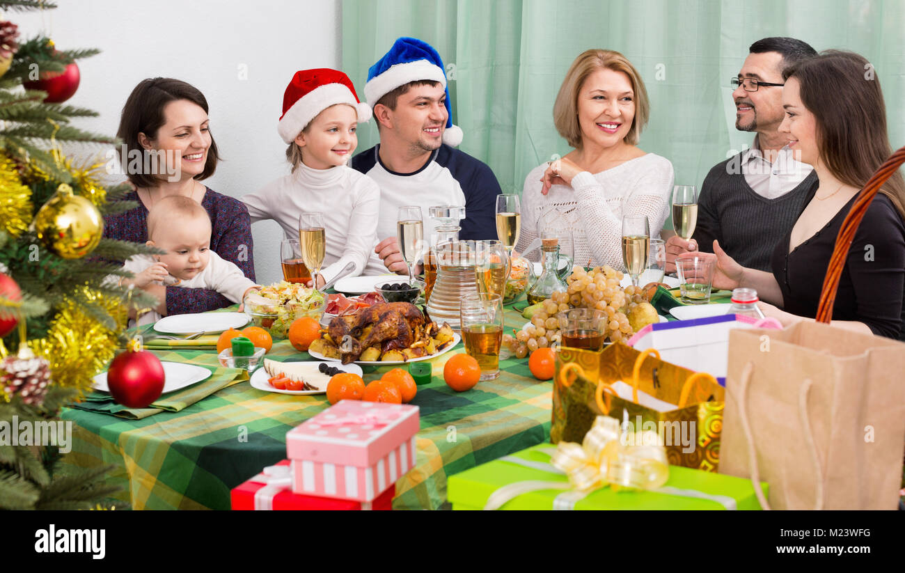 Multigenerational cheerful smiling family sitting at festive table near ...