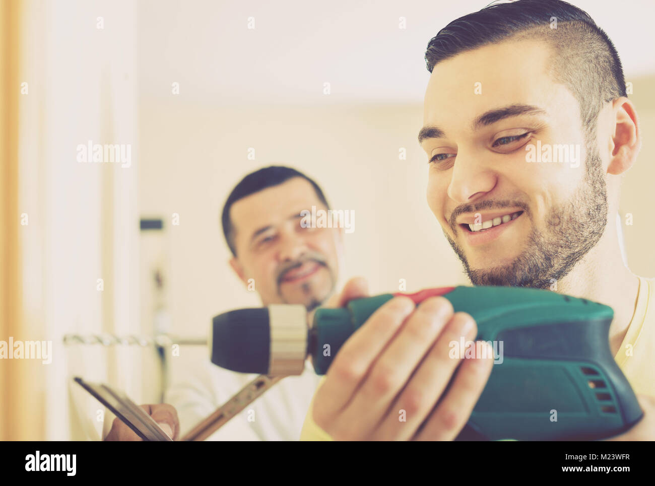 Two smiling male adults with drill and level in house Stock Photo - Alamy
