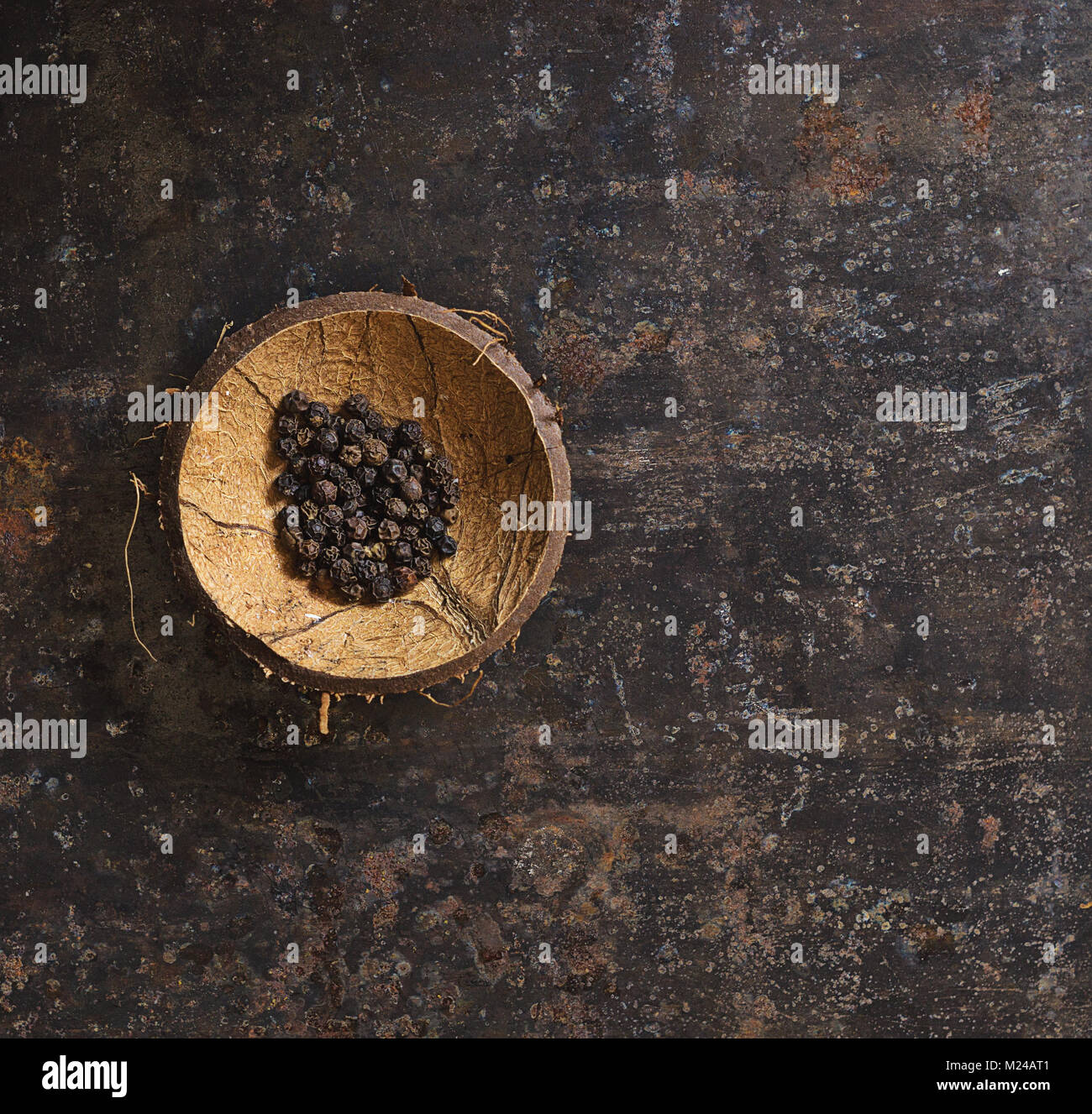 Black pepper in a coconut shell on a rusty metal surface Stock Photo ...