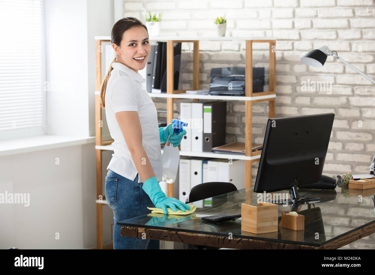 Happy Young Woman Cleaning The Glass Office Desk With Rag Stock Photo ...