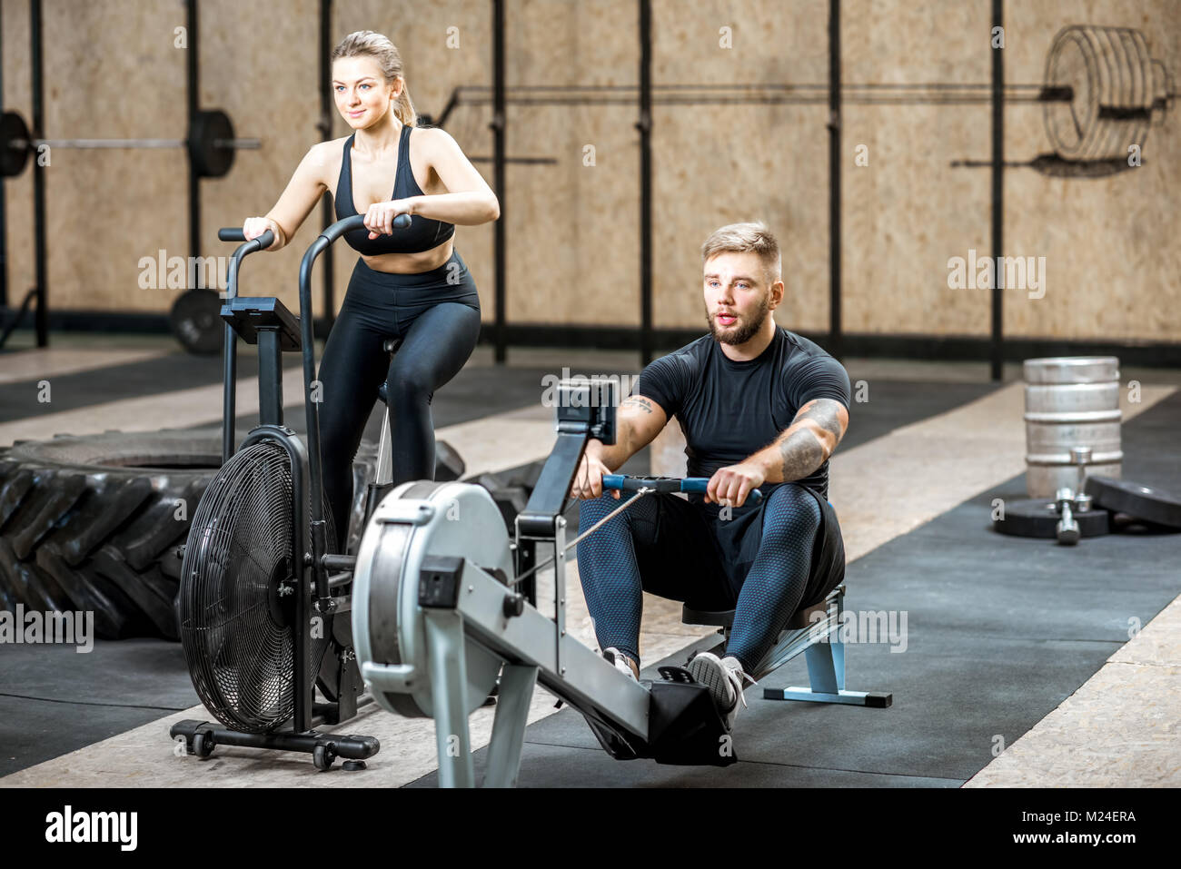 Couple training with exercise machines in the gym Stock Photo - Alamy