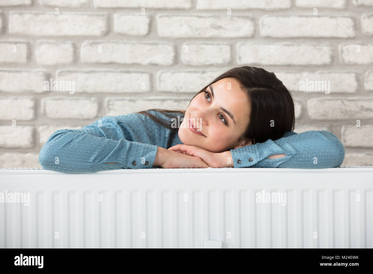Portrait Of A Smiling Woman Behind The Heating Radiator Stock Photo - Alamy