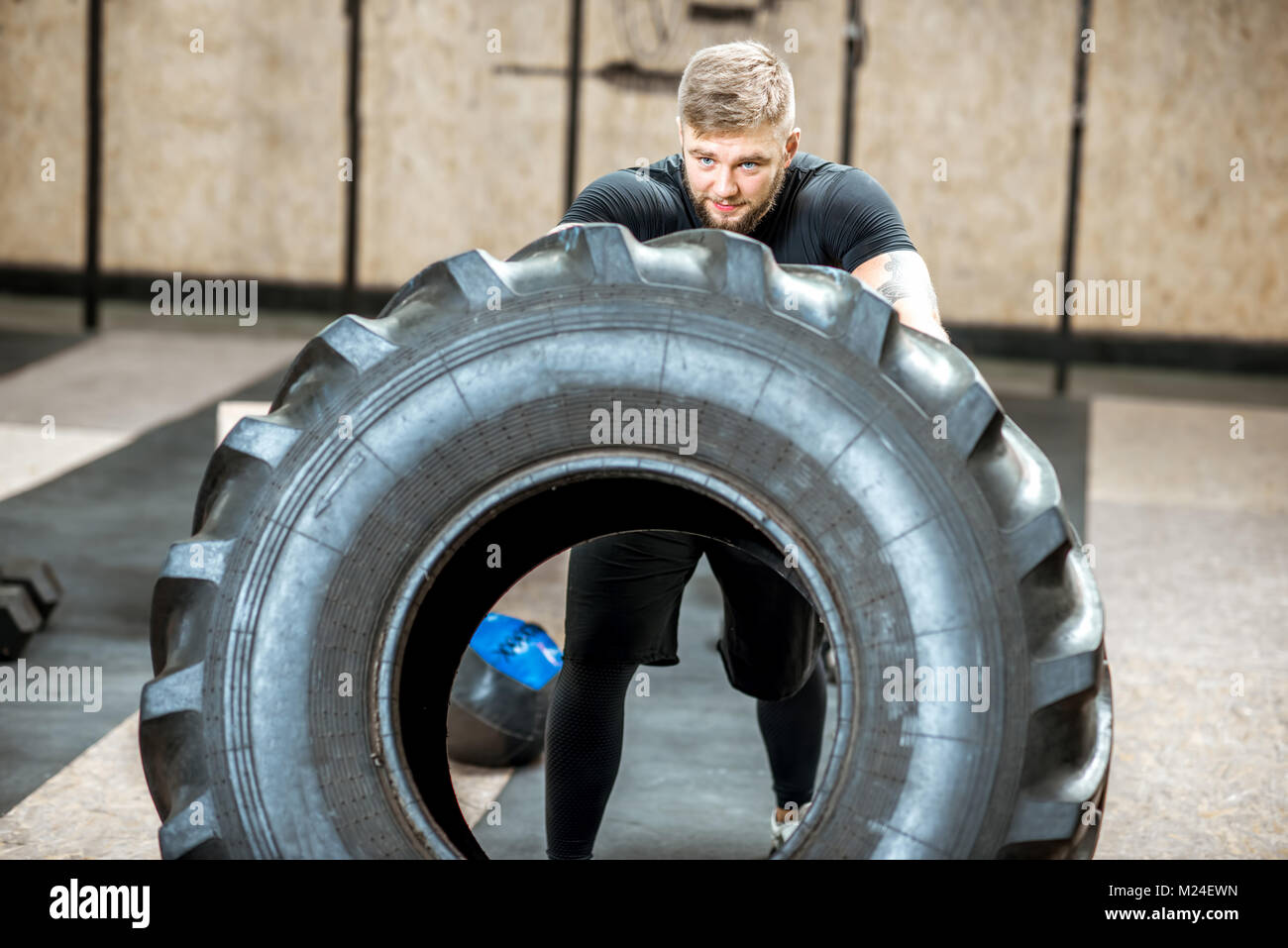 Man pushing a tire in the gym Stock Photo - Alamy