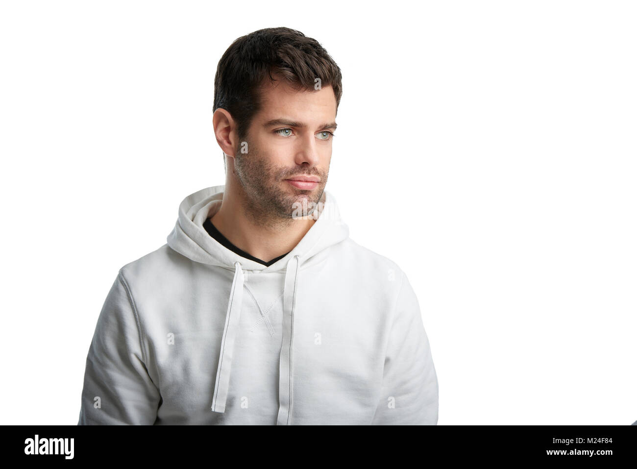 Portrait of young man wearing hoodie while standing at isolated white ...