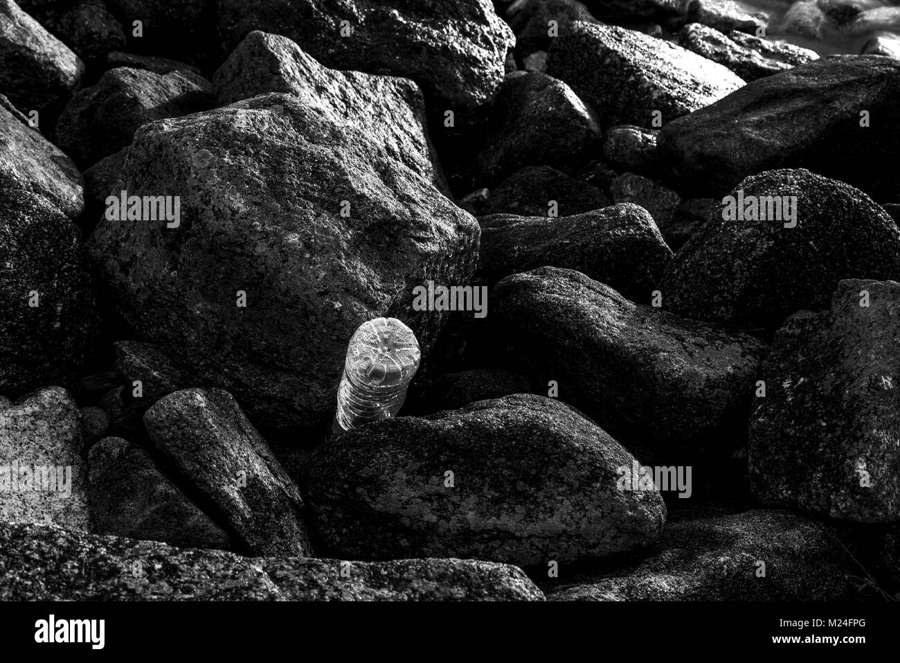 A solitary plastic bottle caught amongst the rocks as the morning sun ...